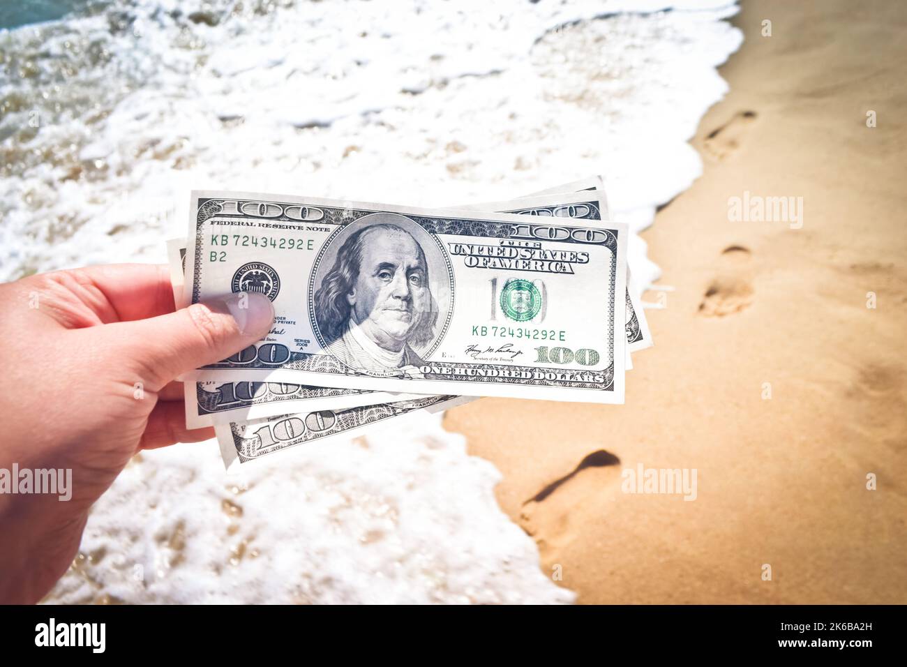 Girl holding money bill of 300 dollars on background of sea ocean waves ...