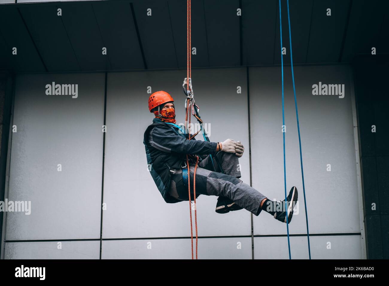 Industrial climber in uniform and helmet rises Stock Photo - Alamy