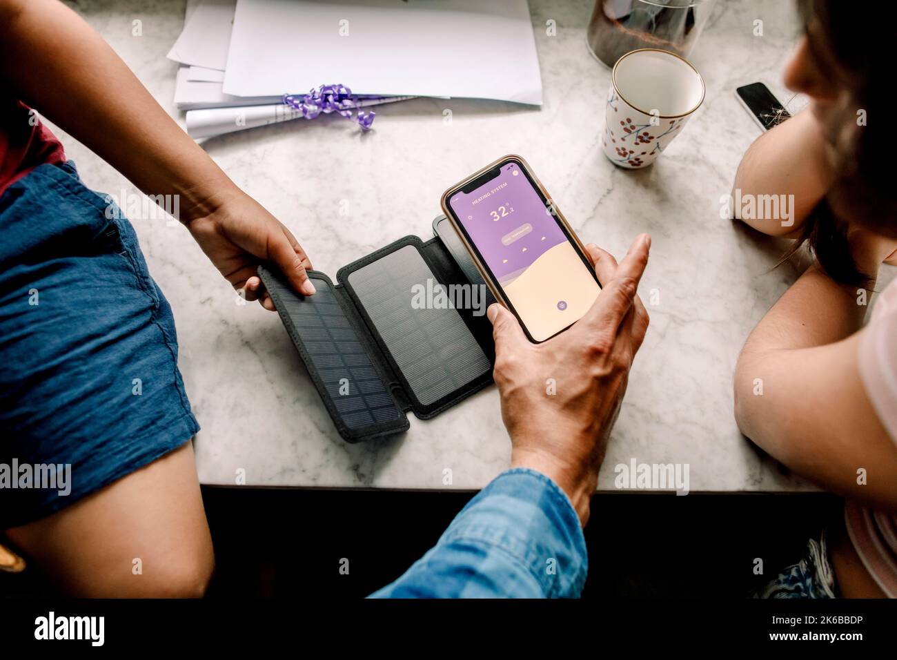 Hand of man holding mobile phone with smart home app over solar panel ...