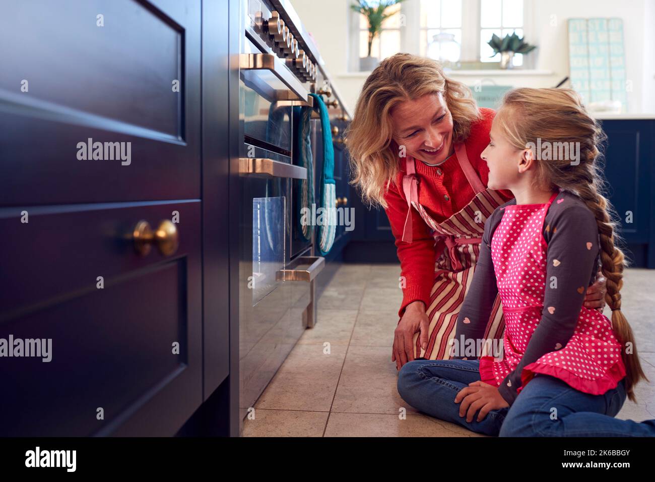 Grandmother And Granddaughter Waiting By Oven In Kitchen At Home For ...