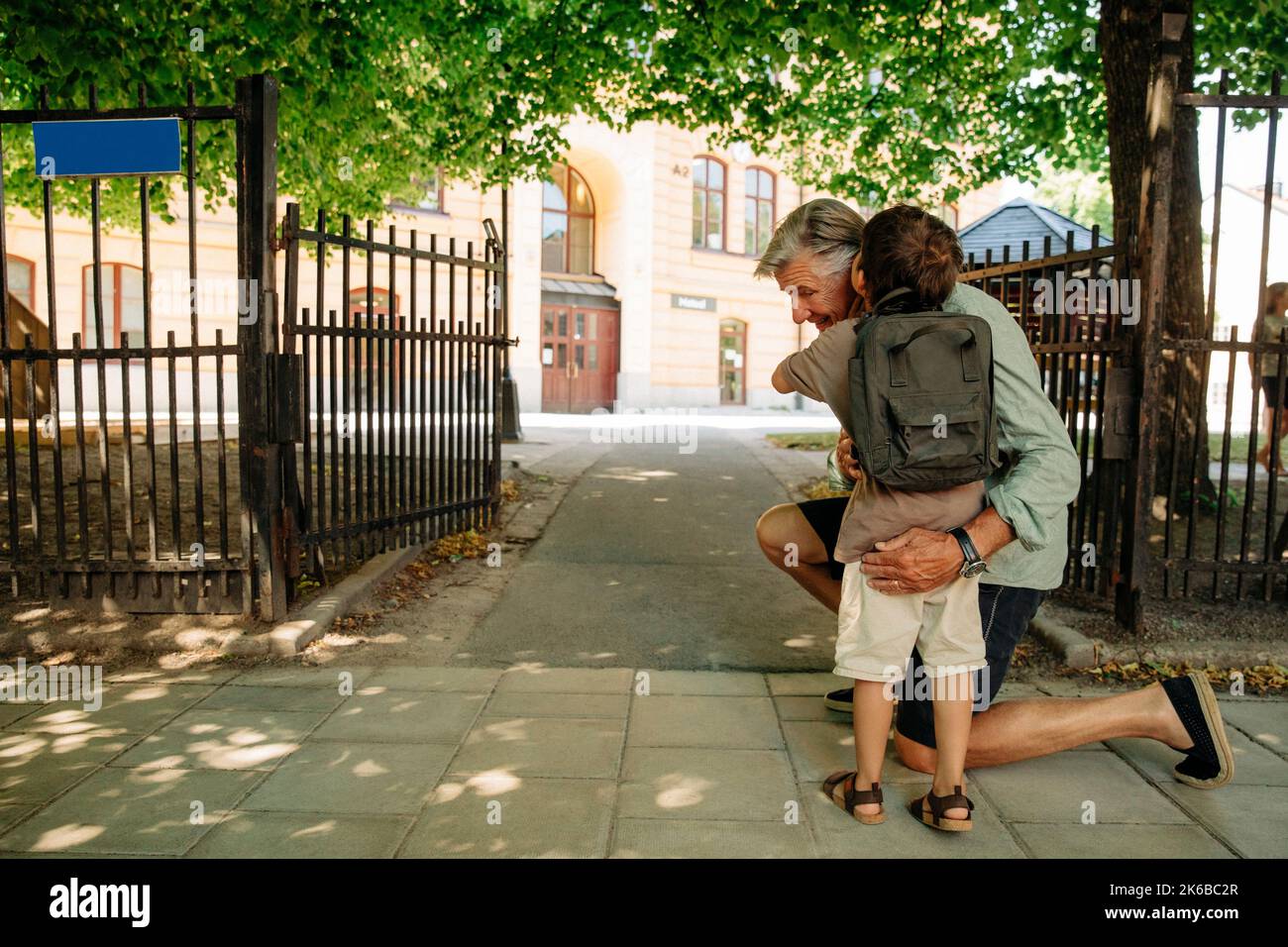 Boy kissing grandfather while standing outside school gate Stock Photo ...