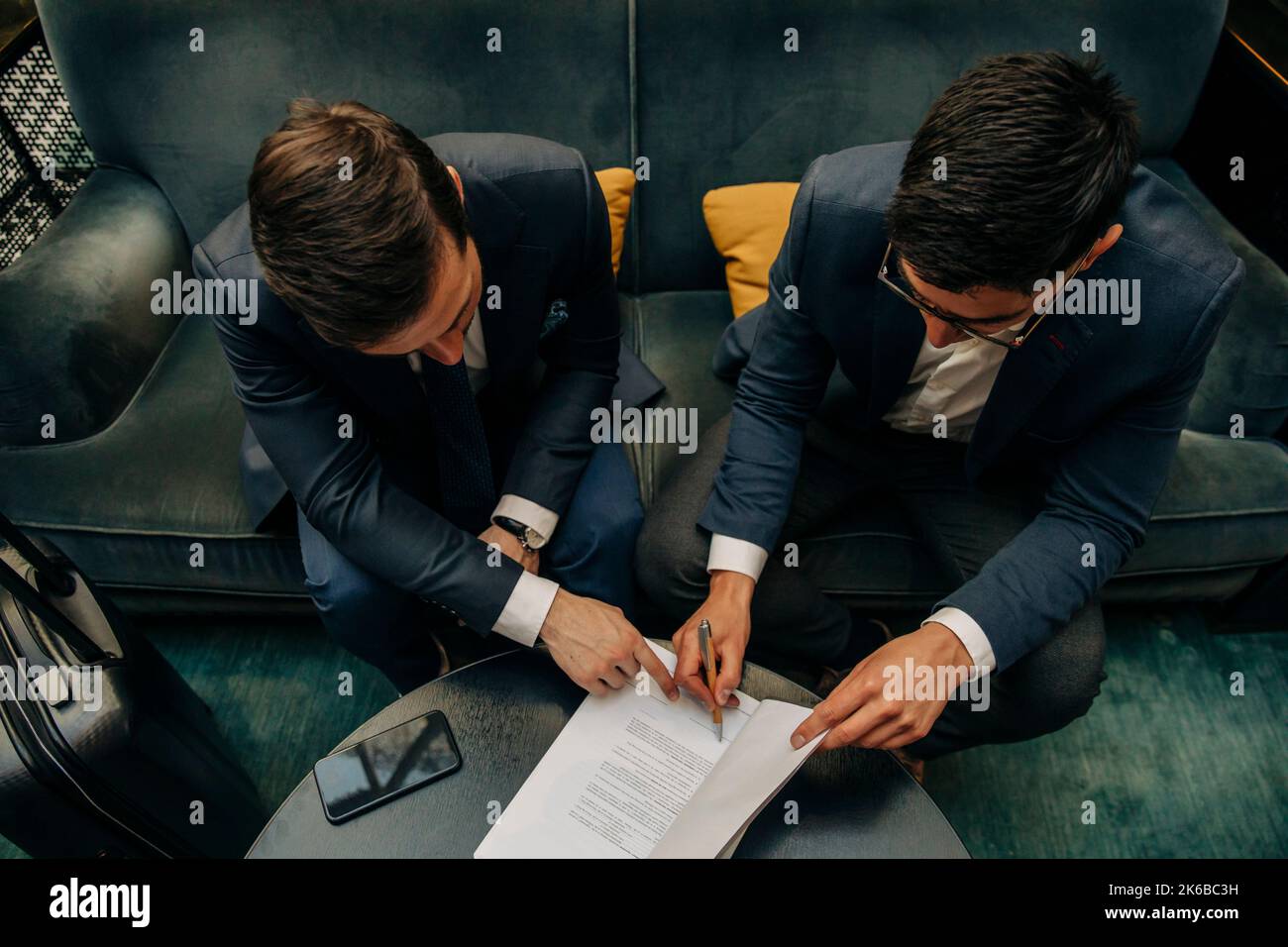 High angle view of businessman signing contract sitting by colleague at ...