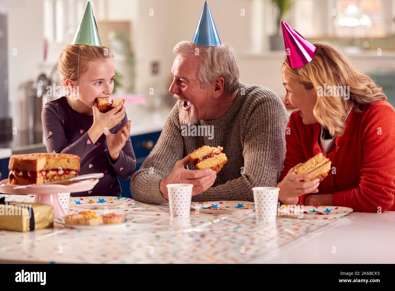 Grandparents With Granddaughter Celebrating Eating Birthday Cake At ...