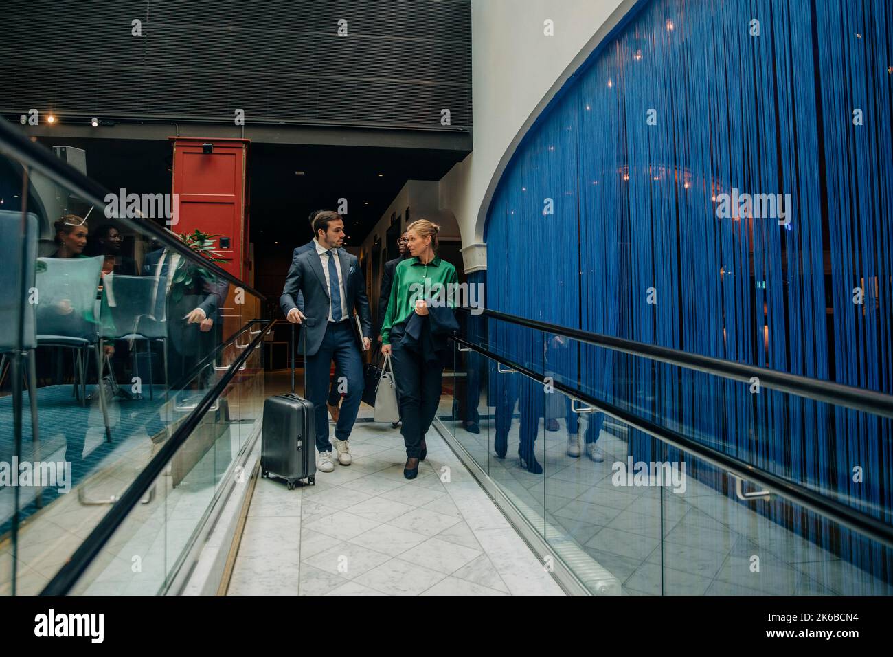 Full length of businessman and businesswoman discussing while walking ...