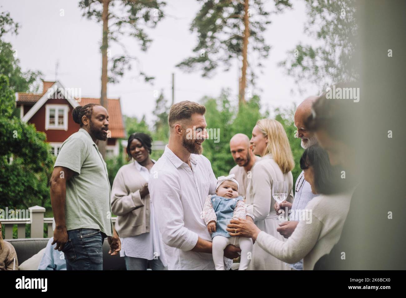 Smiling man introducing daughter to family members at dinner party ...