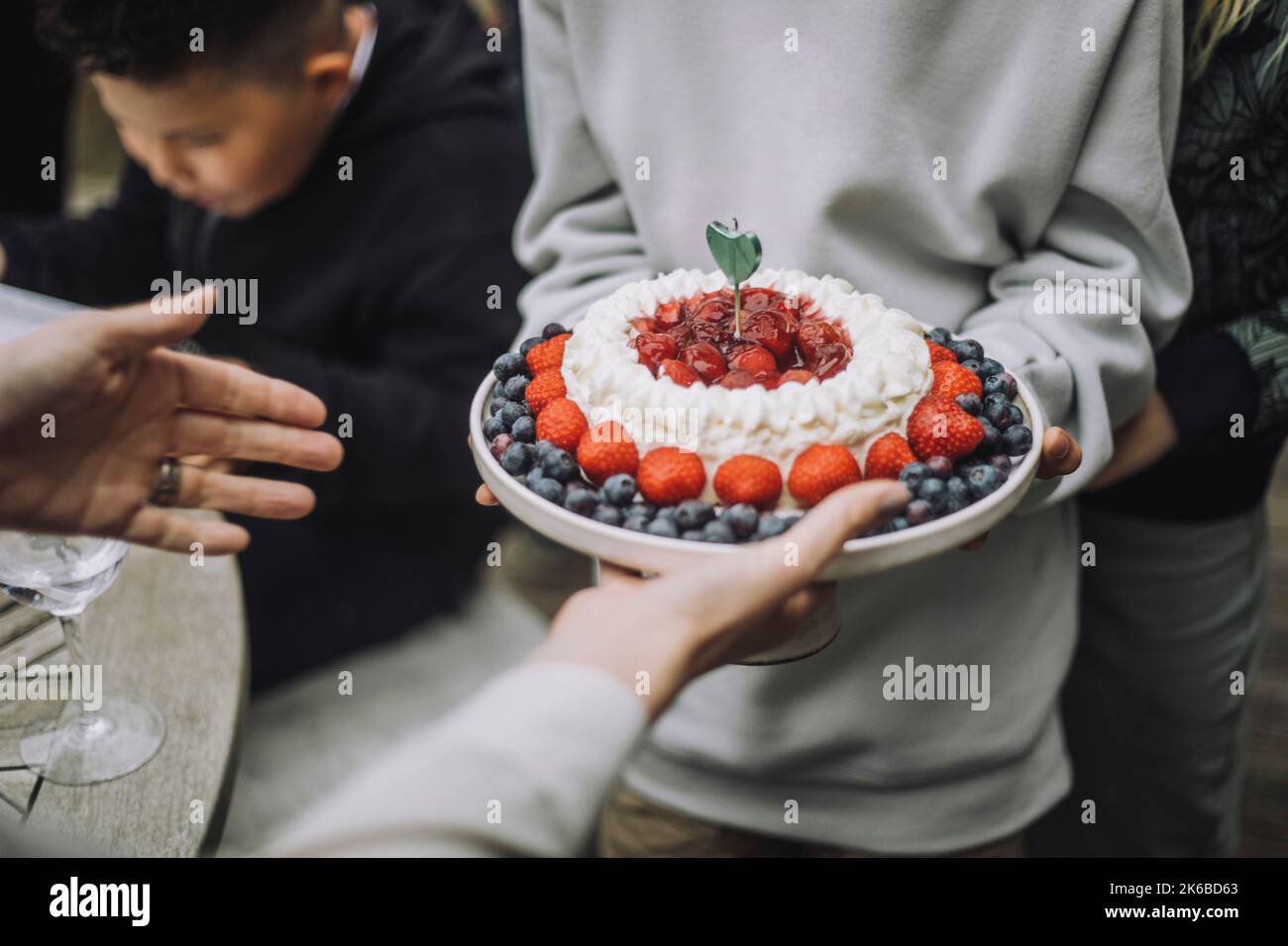 Midsection of boy giving fresh cake to woman at birthday Stock Photo ...