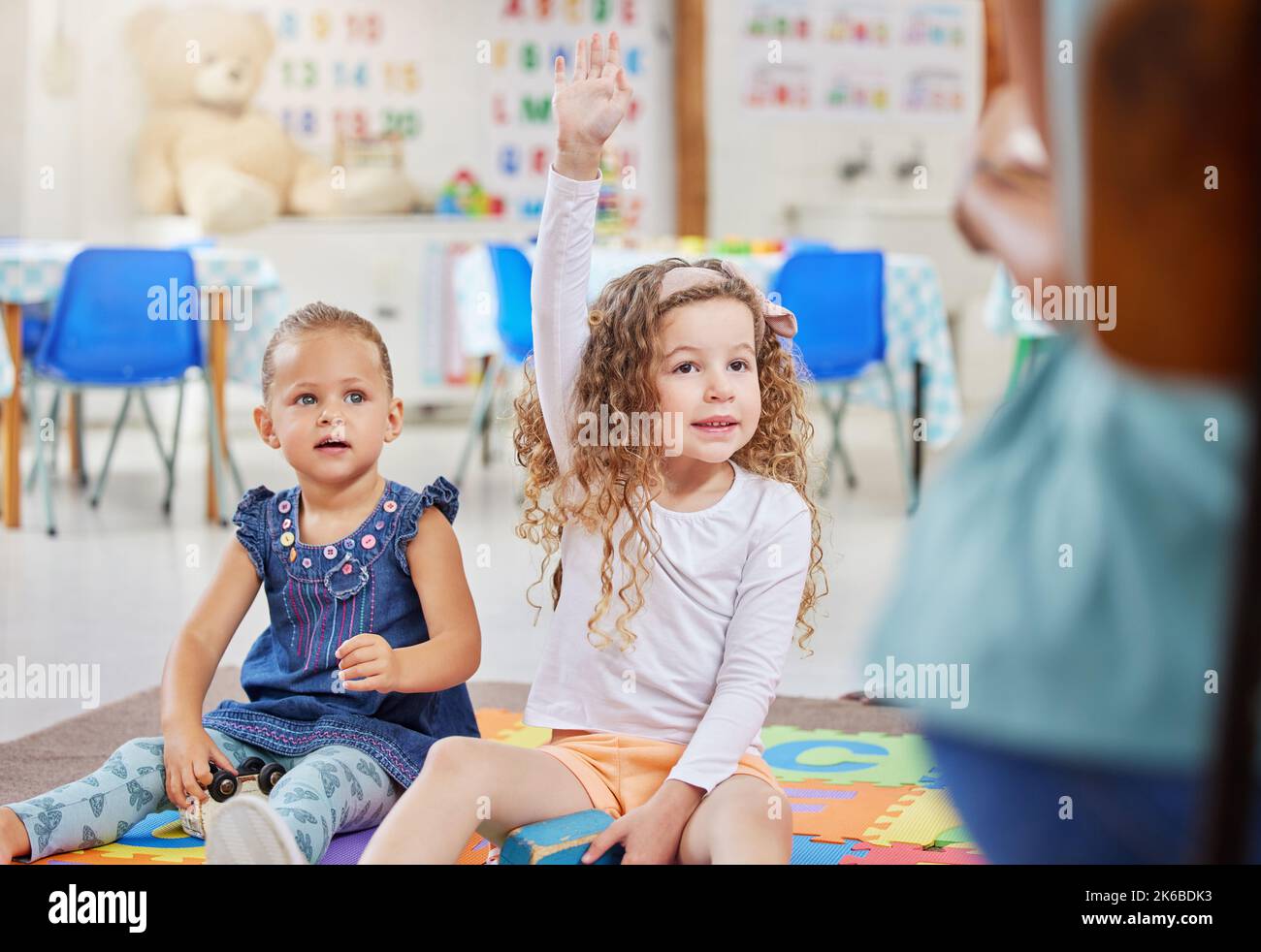 We learn so much at creche. a little girl raising her hand in class ...