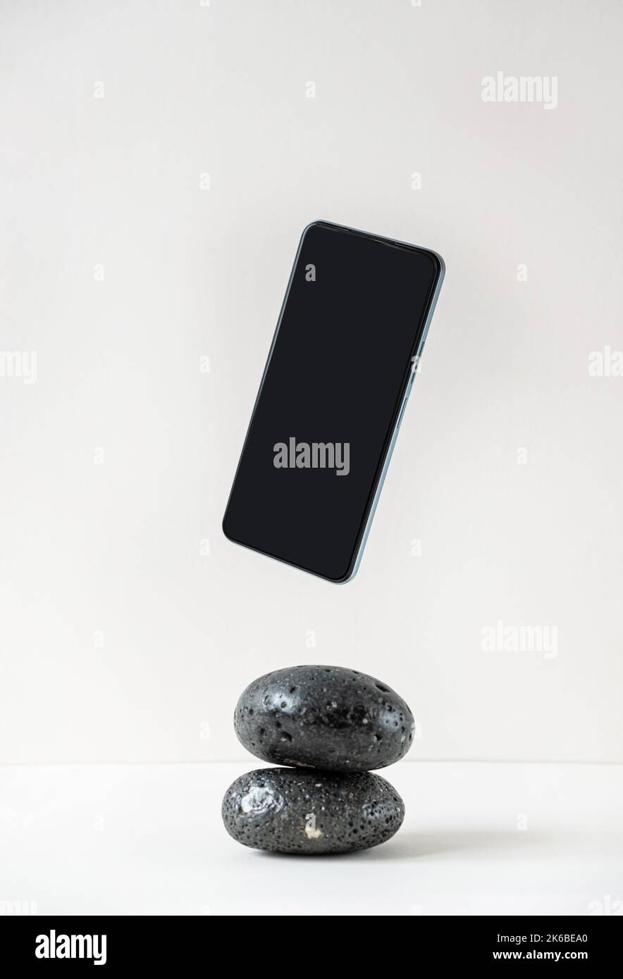 Composition of modern mobile phone with empty screen balancing on black ...