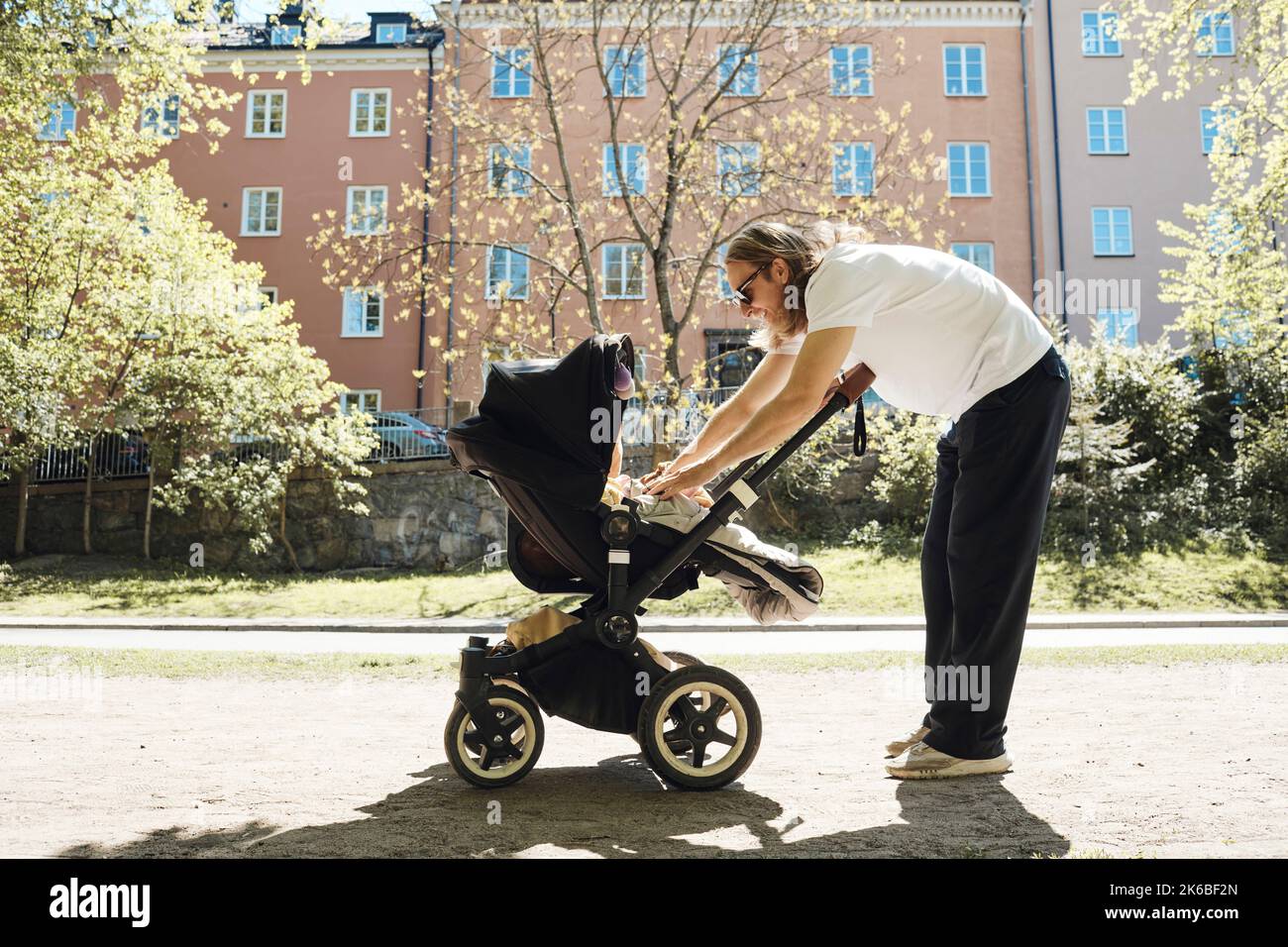 Side view of man playing with daughter in baby stroller while standing ...