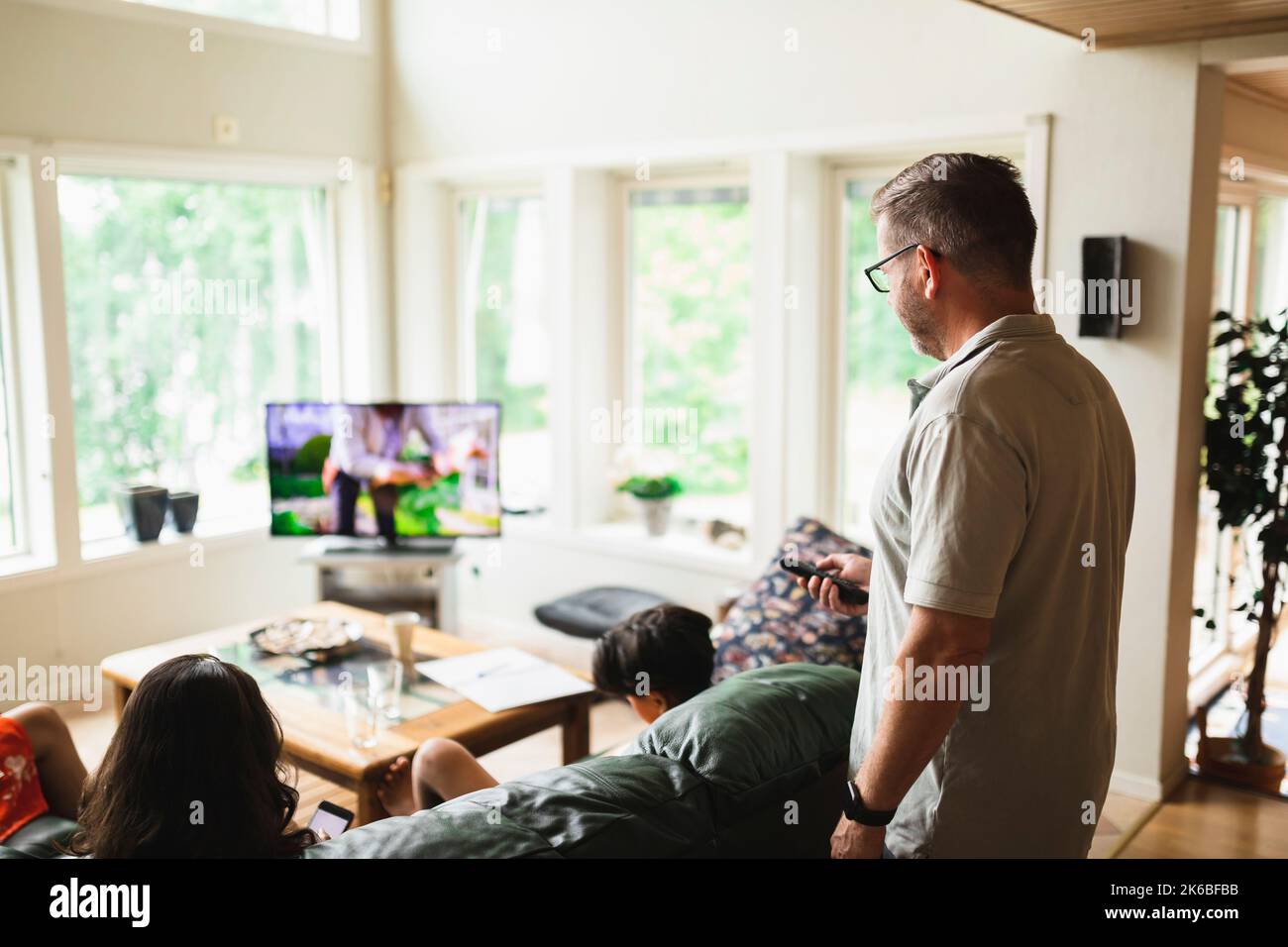 Father changing channels of television through remote control while ...