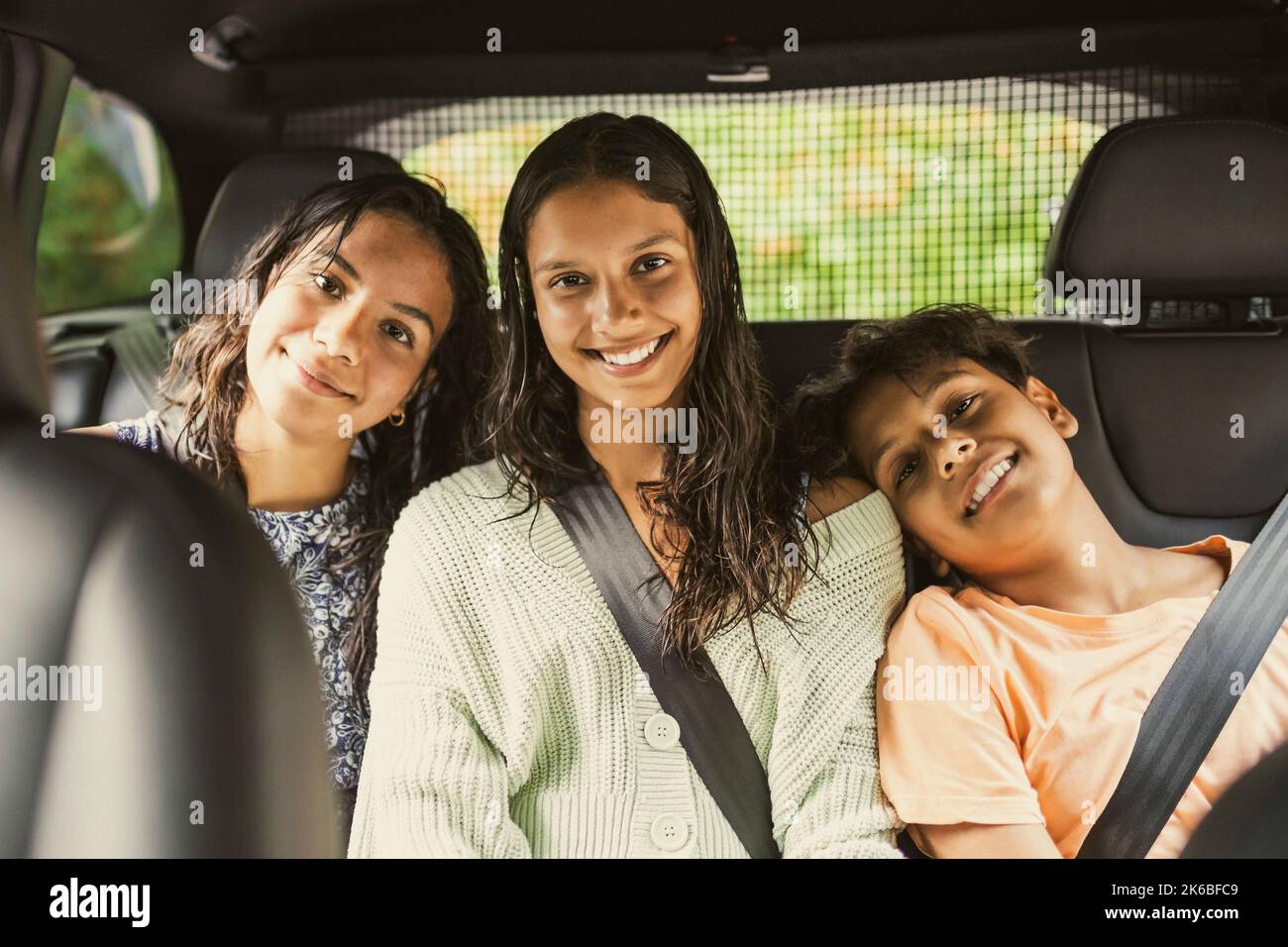 Portrait of smiling siblings wearing seat belt while sitting together ...