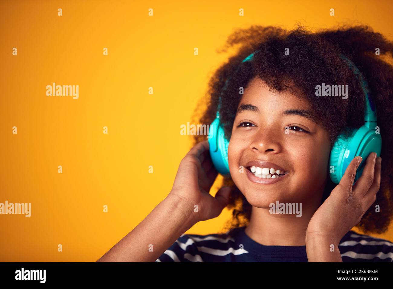 Studio Shot Of Smiling Young Boy Listening To Music On Headphones ...