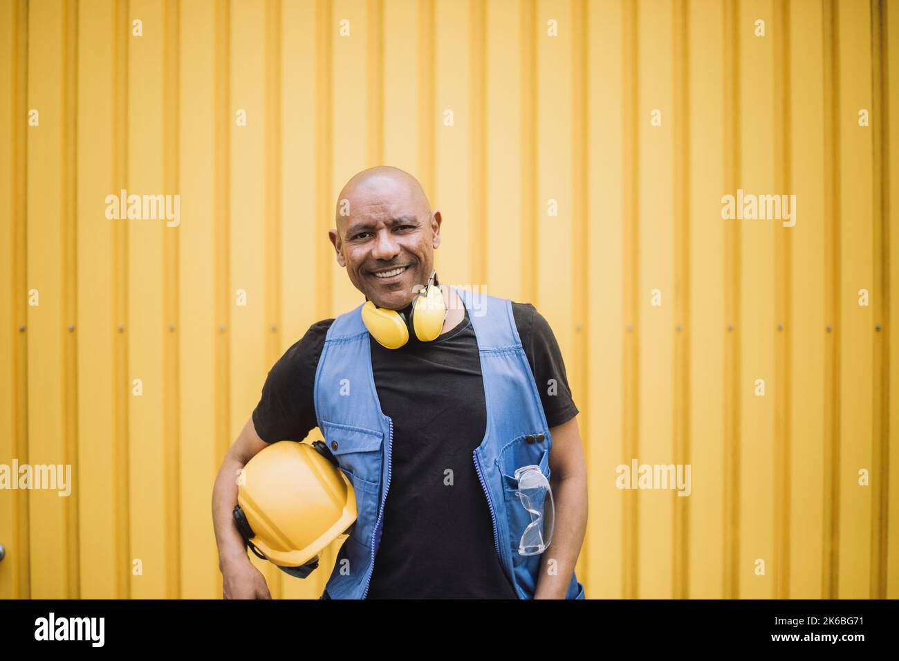 Portrait of happy bald construction worker with hardhat and ear ...