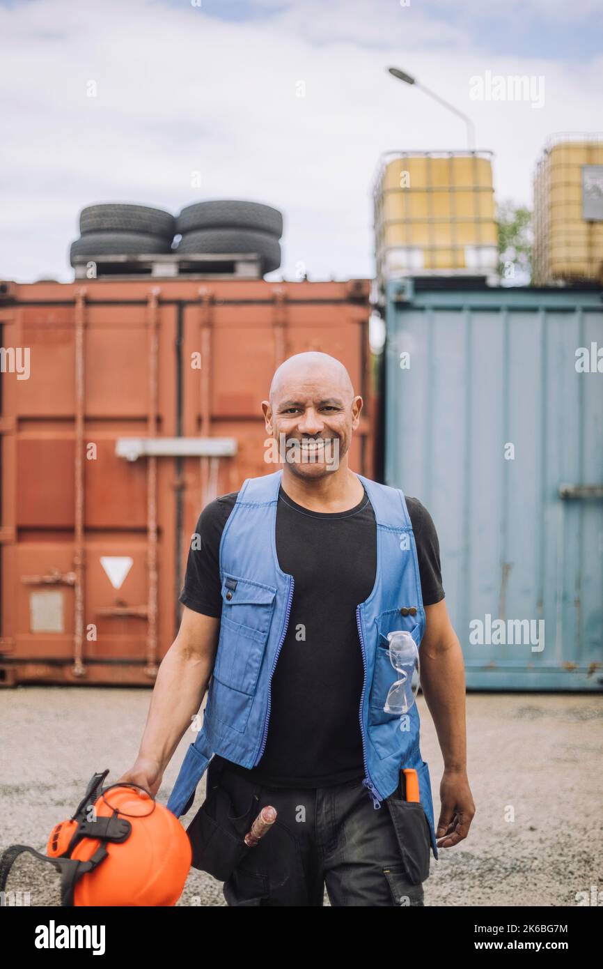 Portrait of happy bald construction worker with hardhat walking at site ...