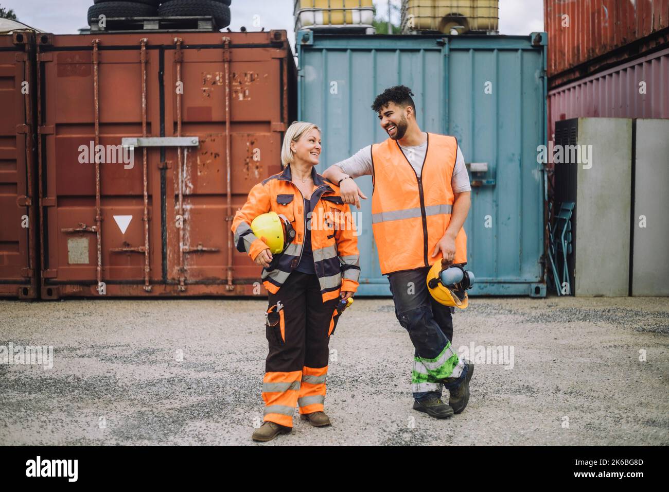 Full length of happy male and female colleagues looking at each other ...