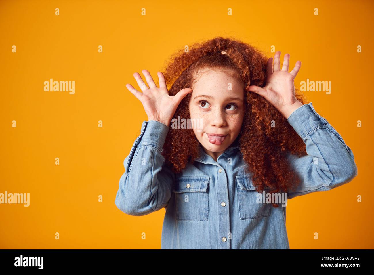 Studio Portrait Of Smiling Young Girl Pulling Funny Face Shot Against ...