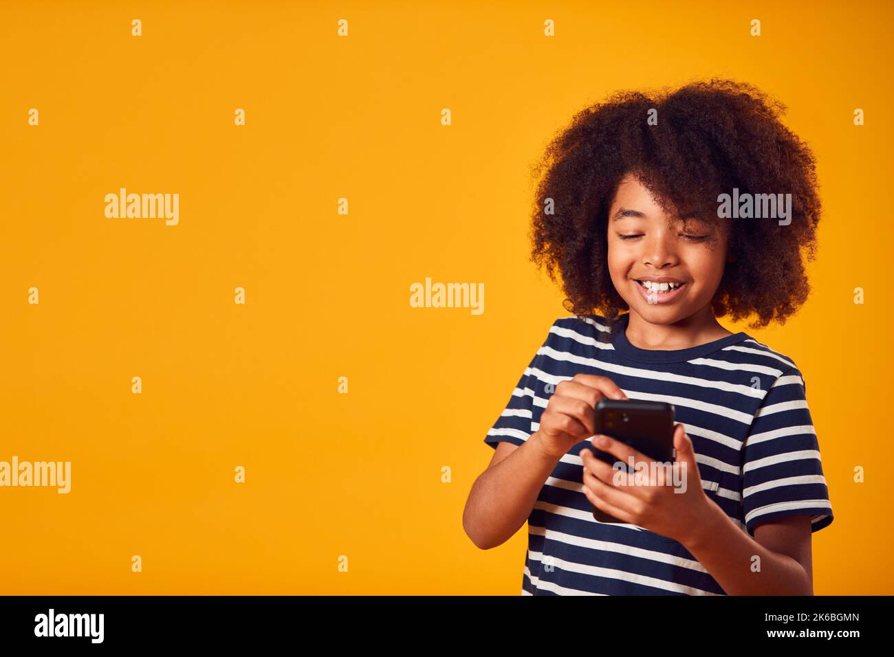 Studio Portrait Of Young Boy Using Mobile Phone Against Yellow ...