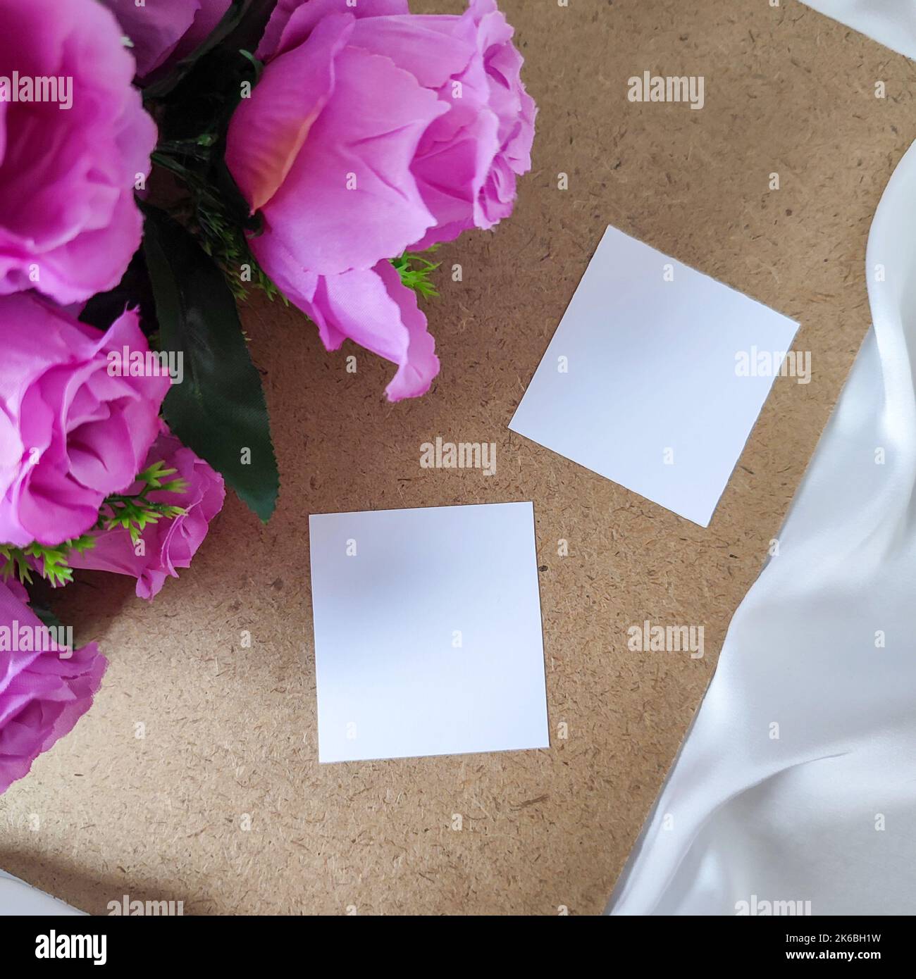 A top view of artificial roses, two white stickers, and craft paper ...