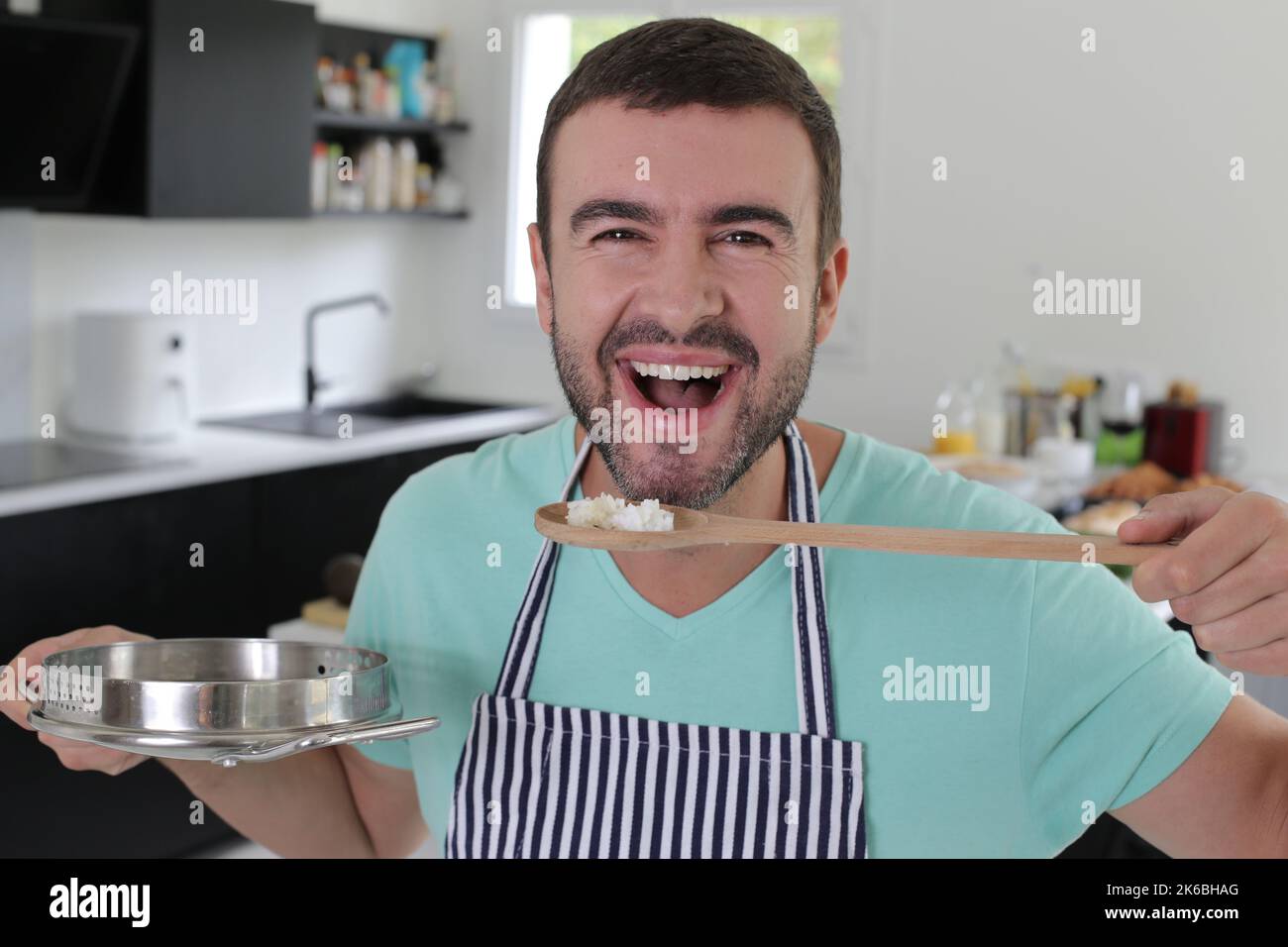 Man tasting some food his is preparing in the kitchen Stock Photo - Alamy
