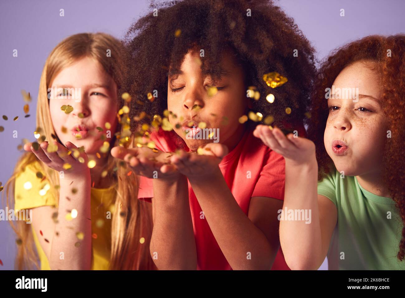 Studio Shot Of Children Blowing Glitter From Hands On Purple Background ...