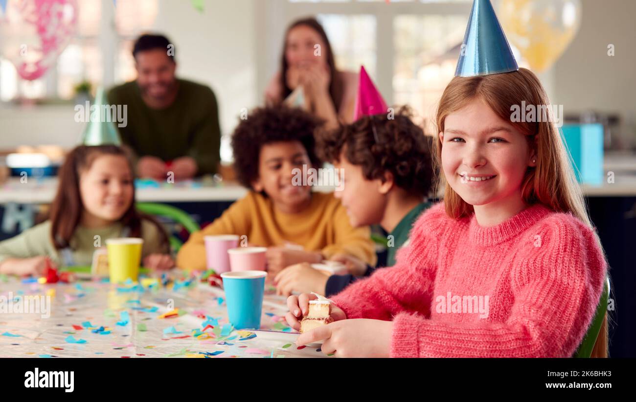 Portrait Of Girl Eating Birthday Cake At Party With Parents And Friends ...