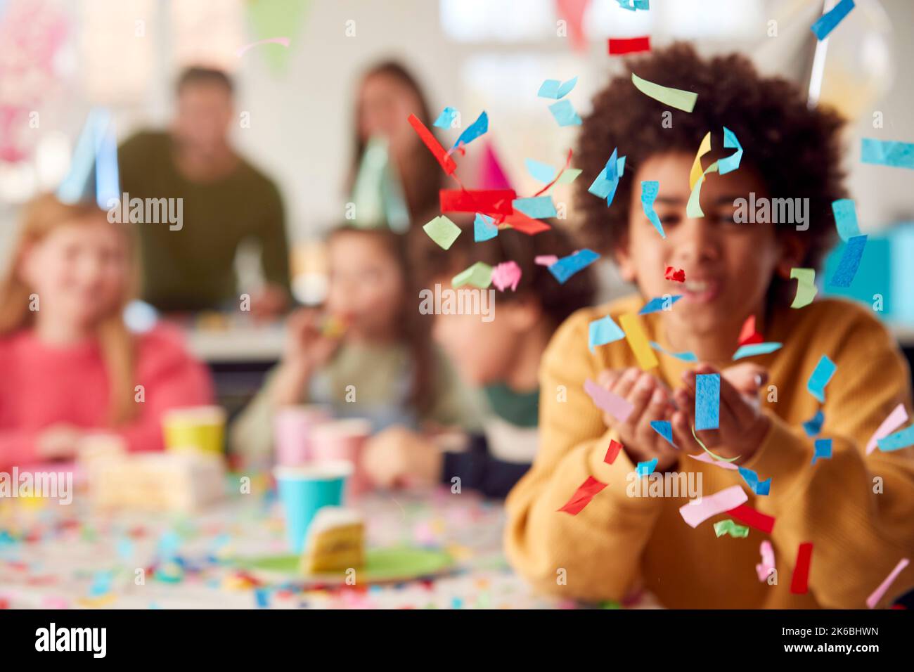 Boy Blowing Confetti At Camera At Birthday Party With Friends And ...