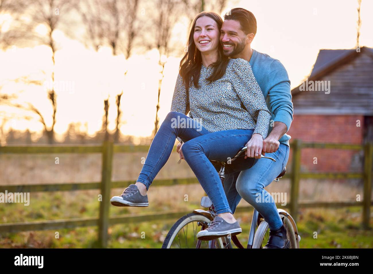 Couple Riding Bike Through Countryside With Woman Sitting On Handlebars ...