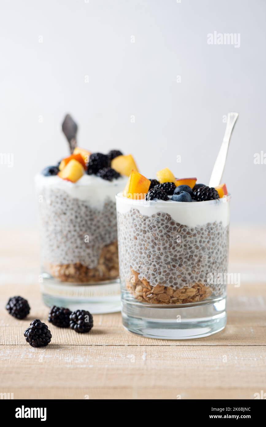 Vegan chia pudding jar with granola and fruits over grey background ...