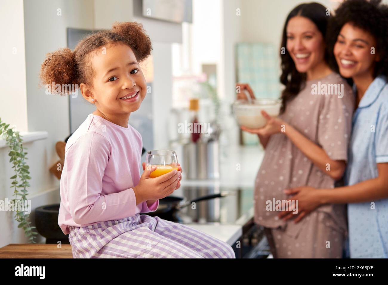 Pregnant Family With Two Mums Wearing Pyjamas Making Morning Pancakes ...