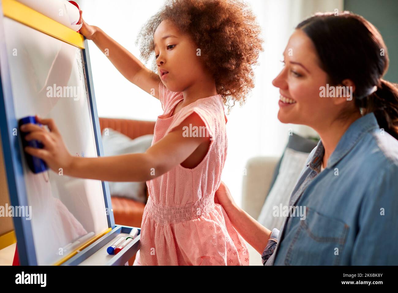 Mother And Daughter Having Fun Drawing Picture On Whiteboard At Home ...