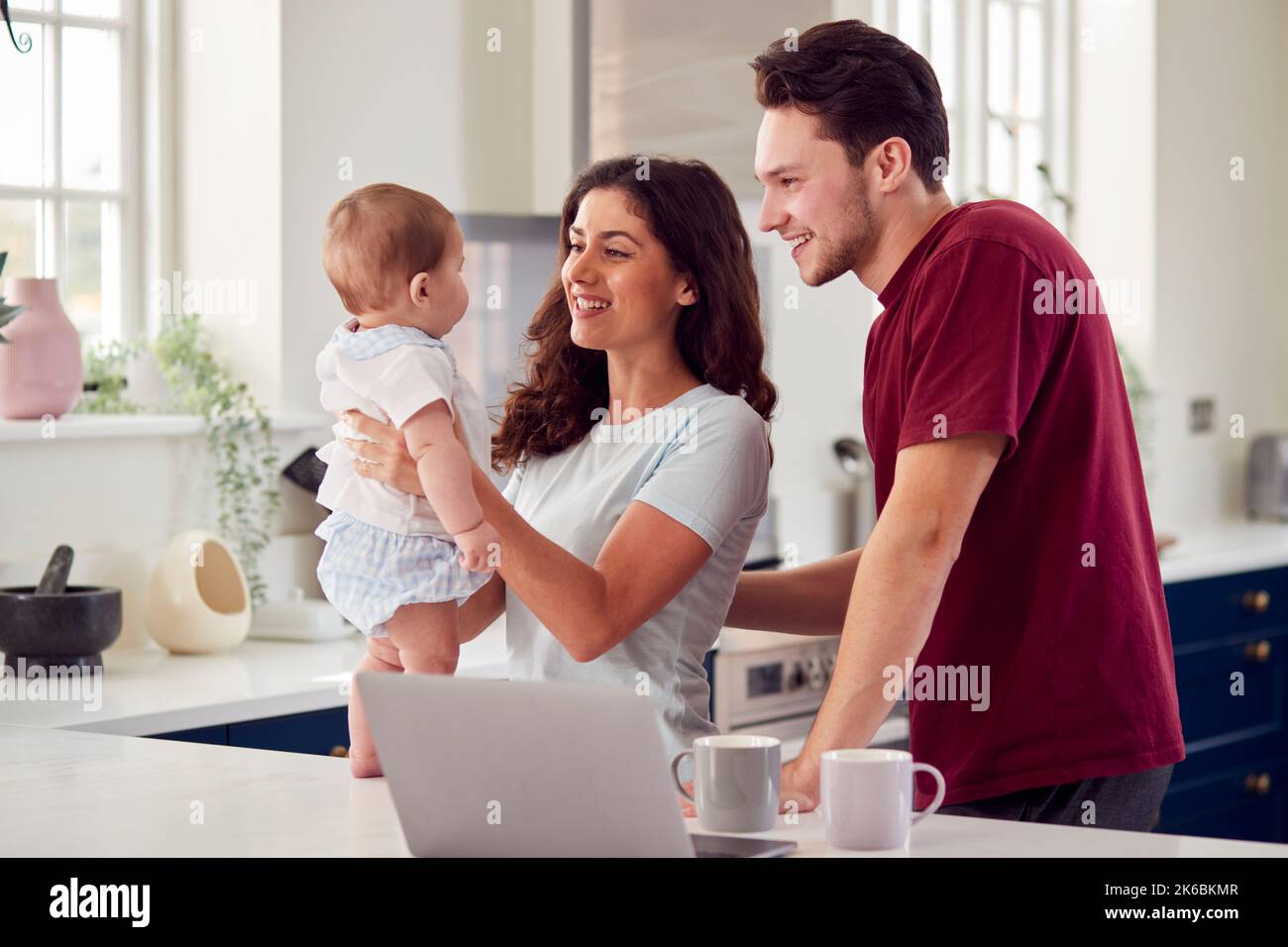 Loving Transgender Family With Baby At Home Together Looking At Laptop ...