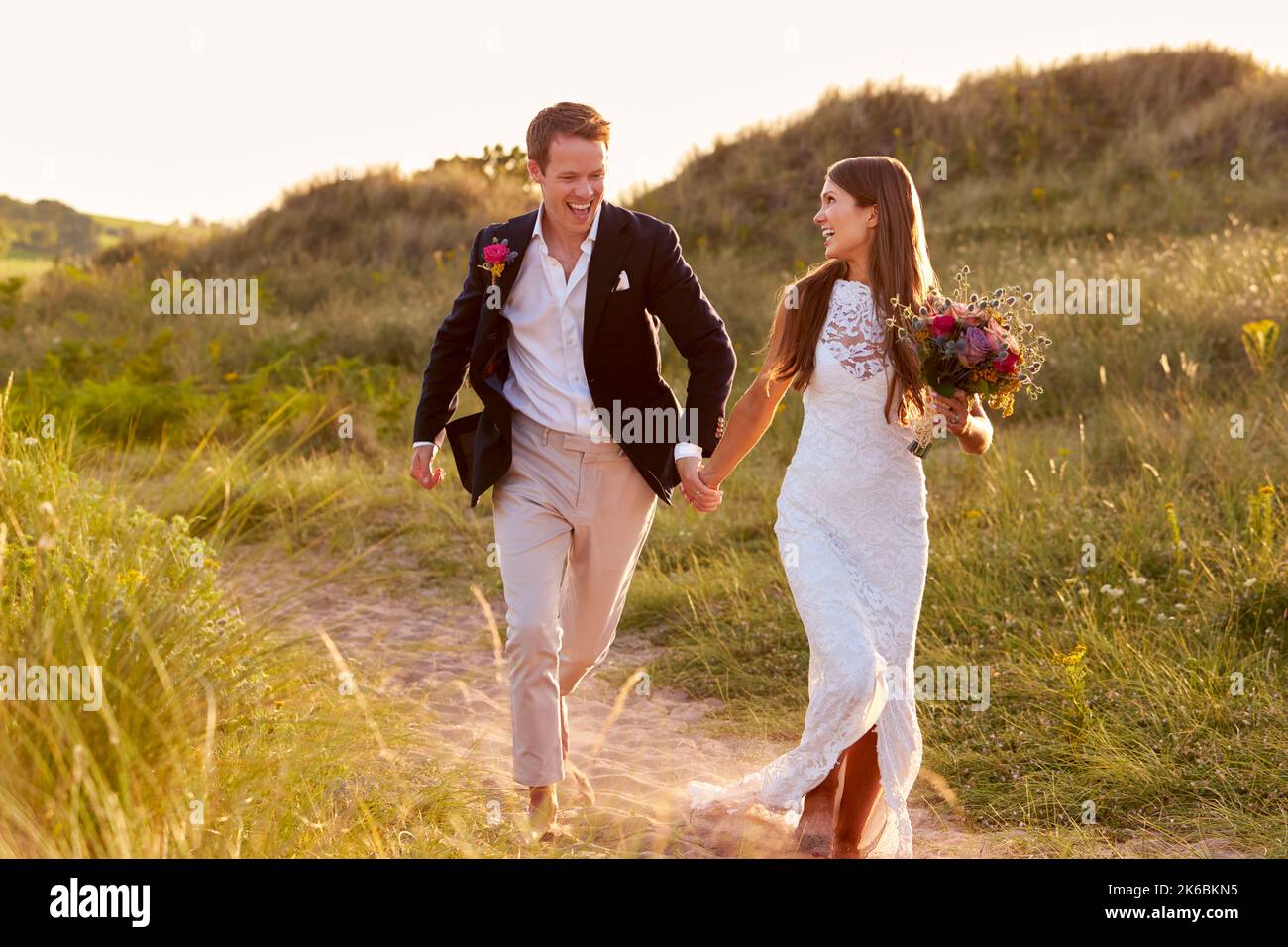 Romantic Married Couple Celebrating Beach Wedding Running In Dunes ...