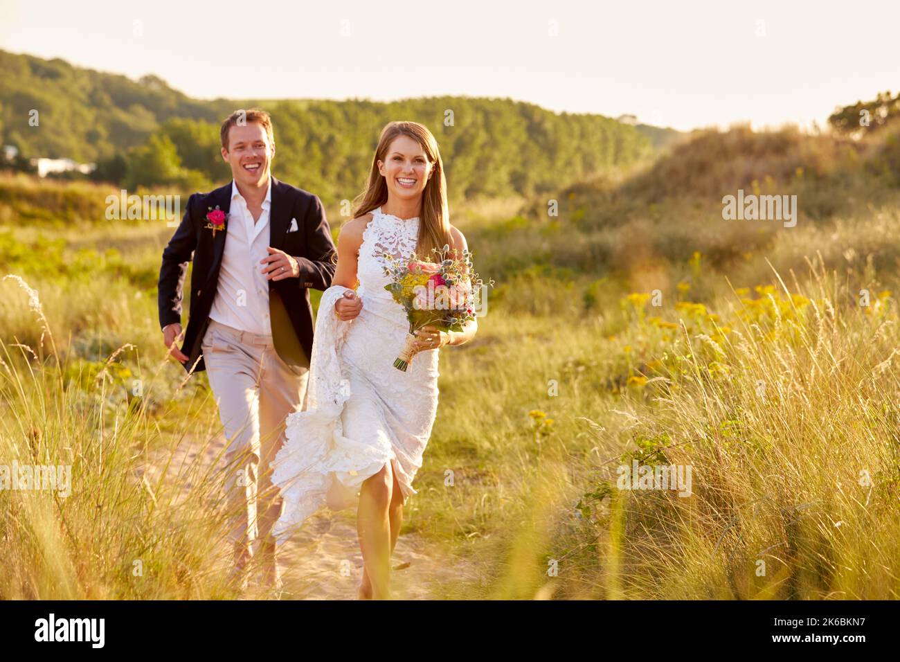Romantic Married Couple Celebrating Beach Wedding Running In Dunes ...