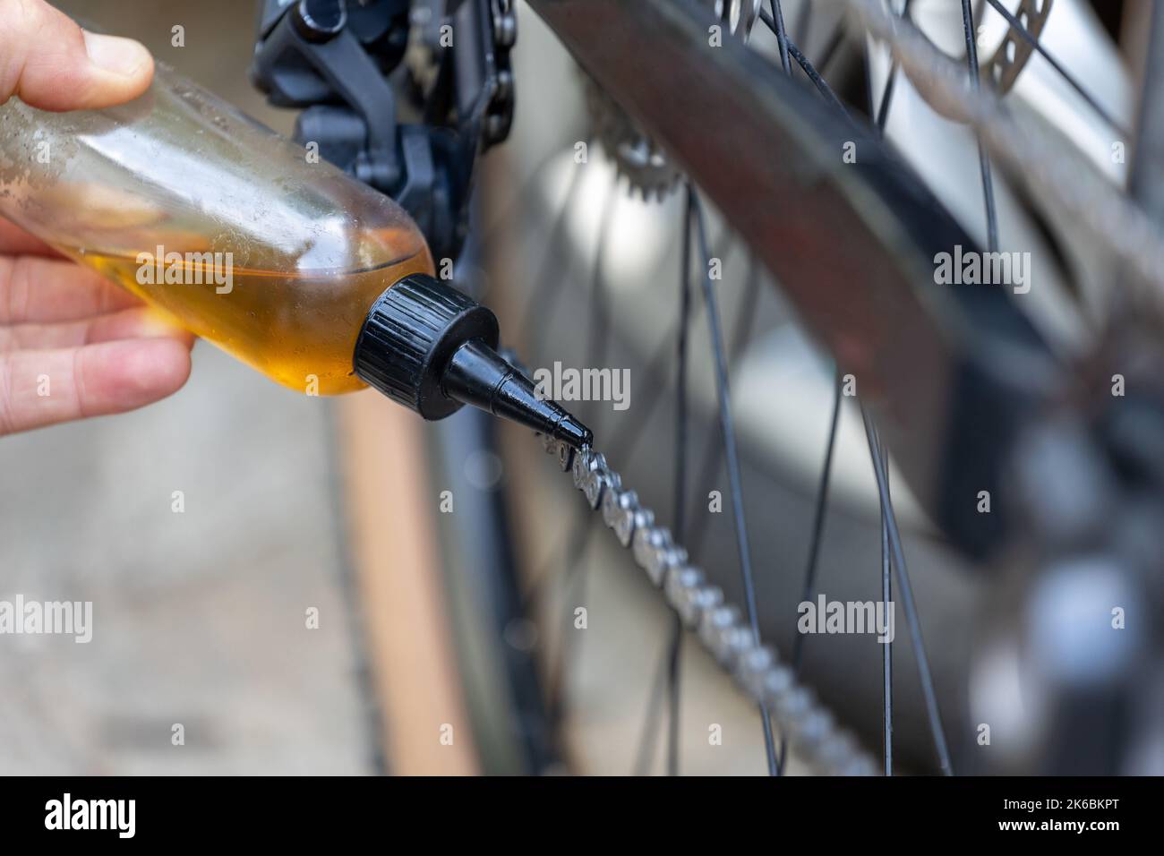 Close up of male hand lubricating bicycle chain with oil from tube ...