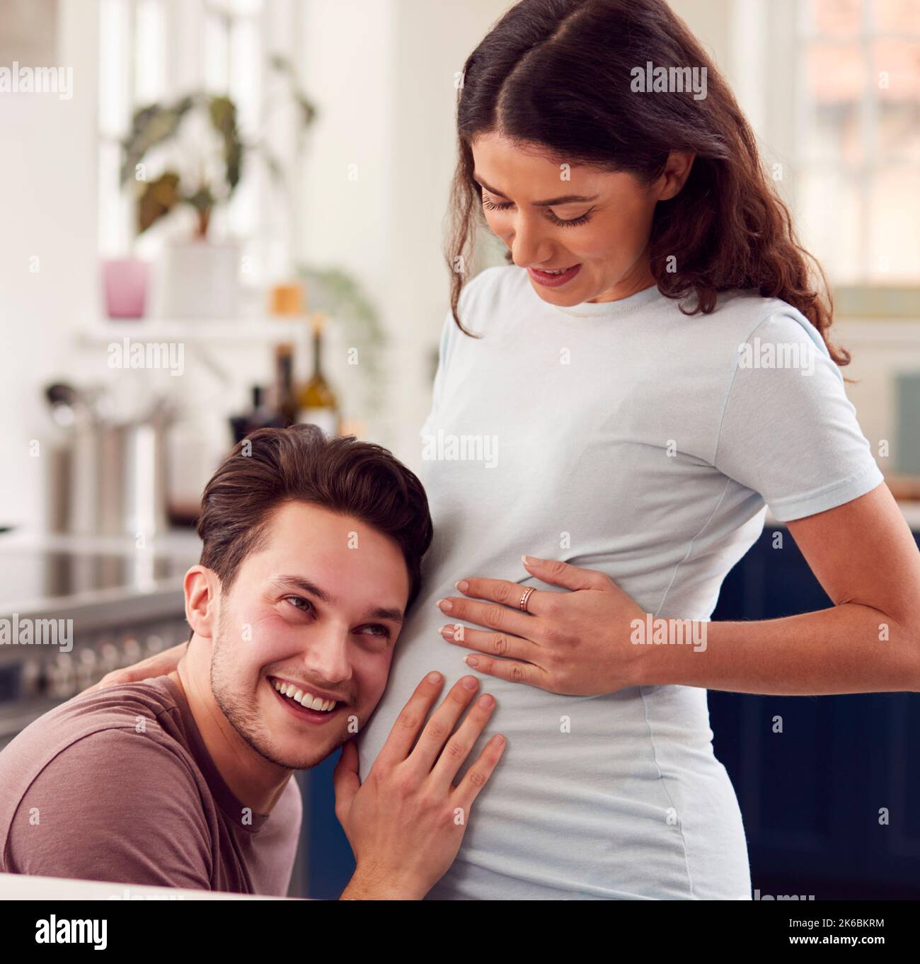 Excited Pregnant Transgender Couple At Home In Kitchen With Man ...