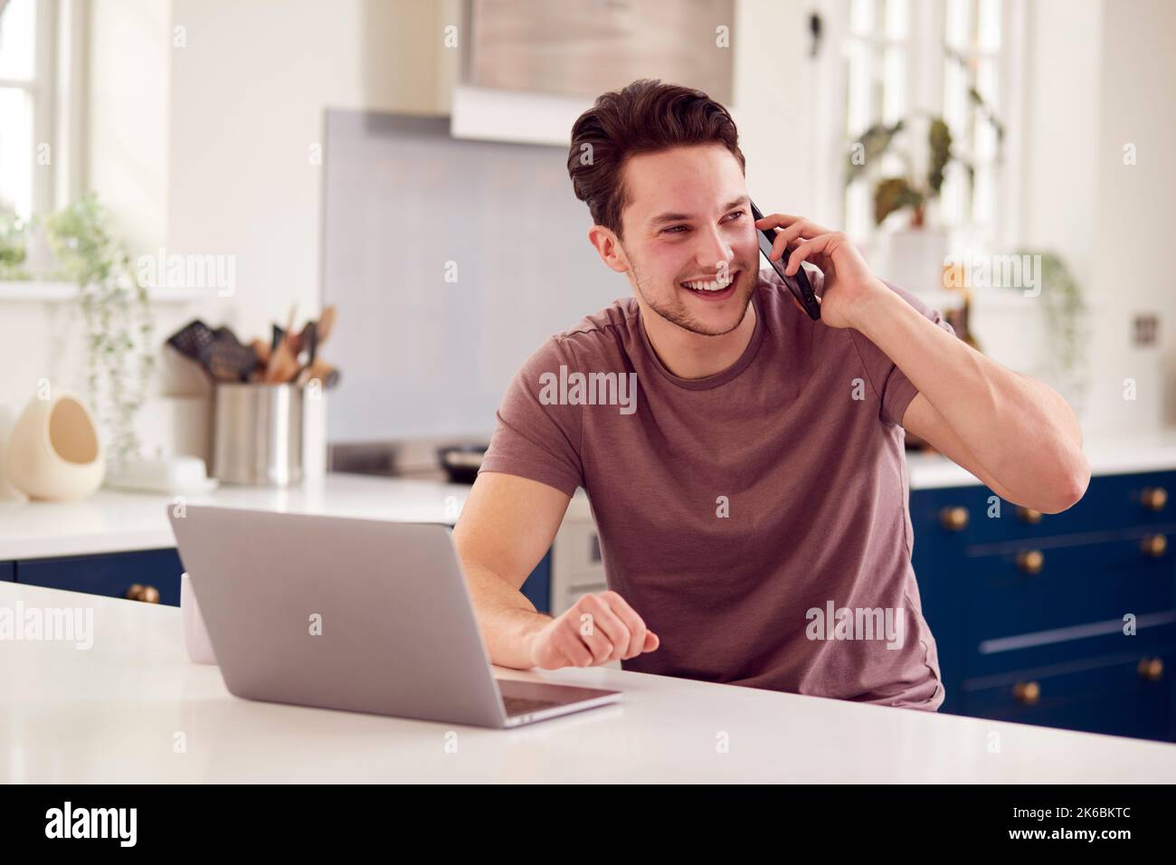 Transgender Man Using Mobile Phone Working From Home Using Laptop On ...
