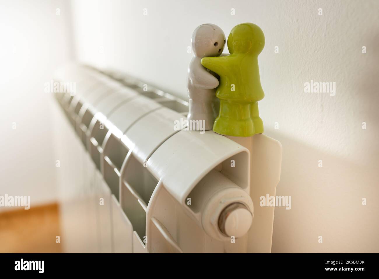 Two figures warming in hug on cold radiator. Energy crisis concept ...