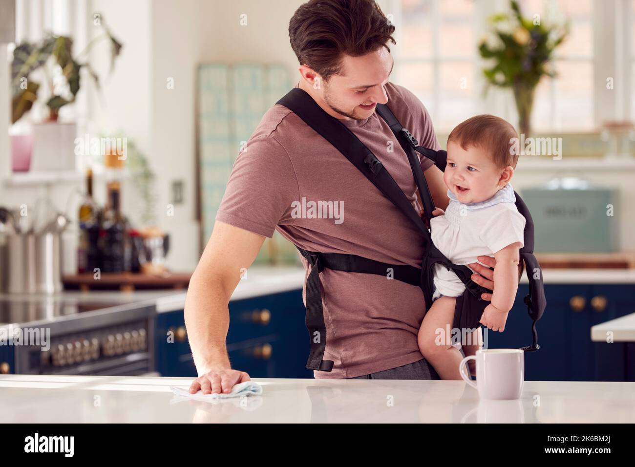 Transgender Father Cleaning Kitchen Looking After Baby Son In Sling ...