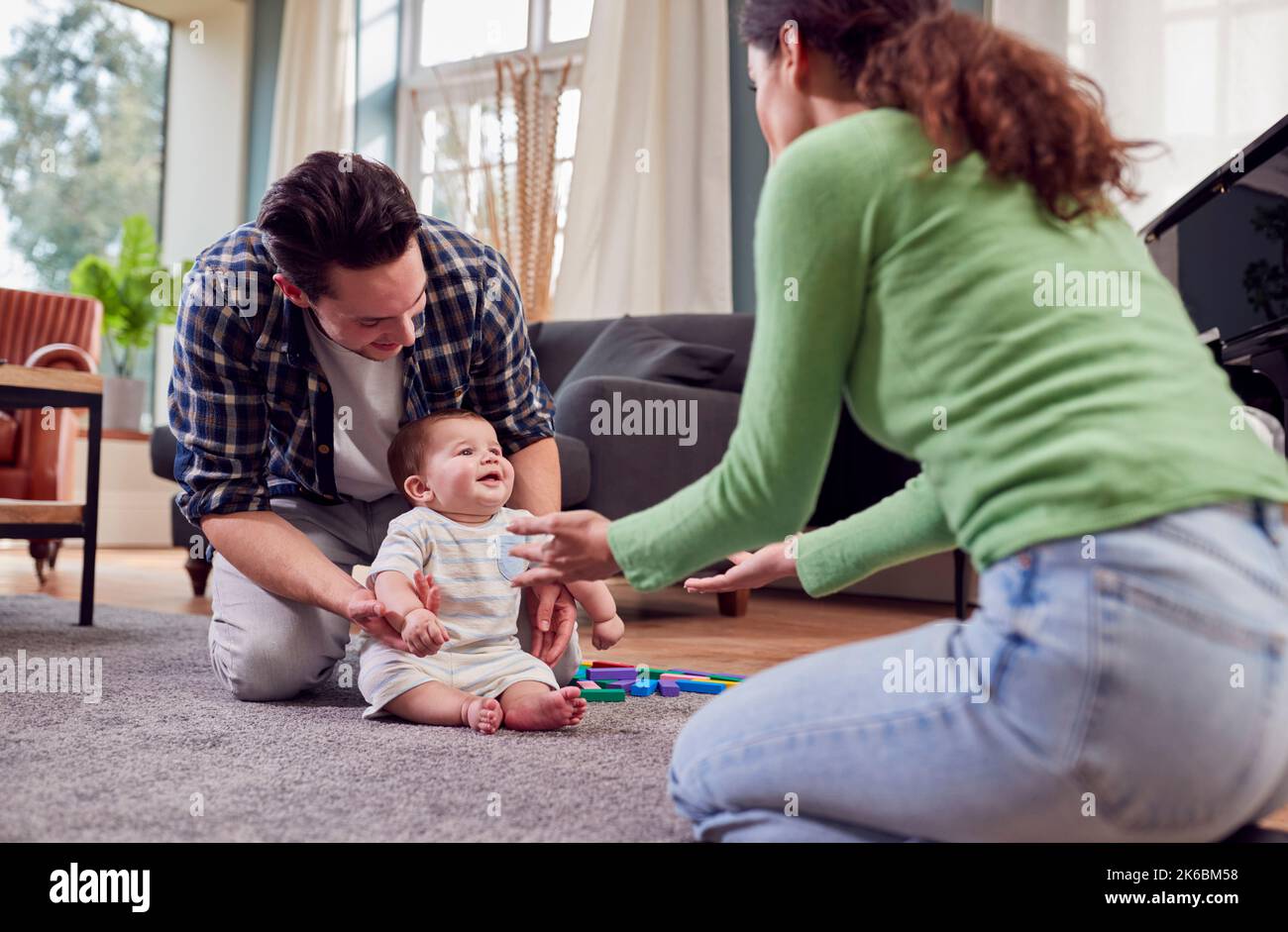 Transgender Family Encouraging Baby To Take First Steps In Lounge At ...