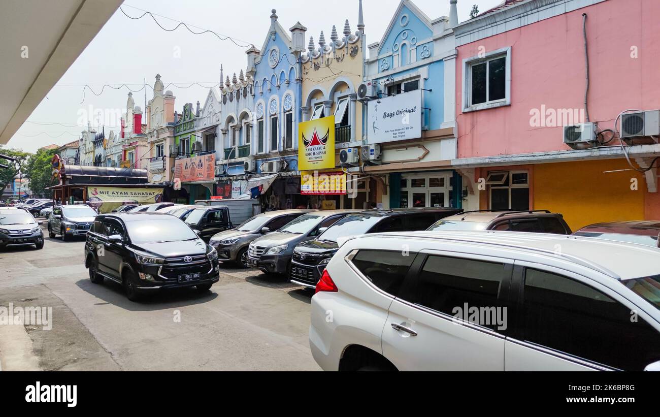 View of cars moving and parking and shops at busy traditional market ...