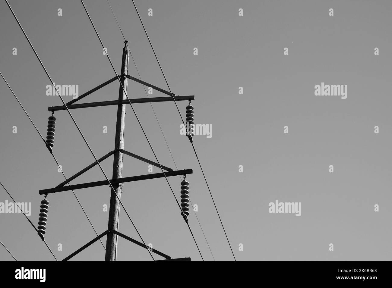 Typical industrial power lines crossing the countryside in a black and ...