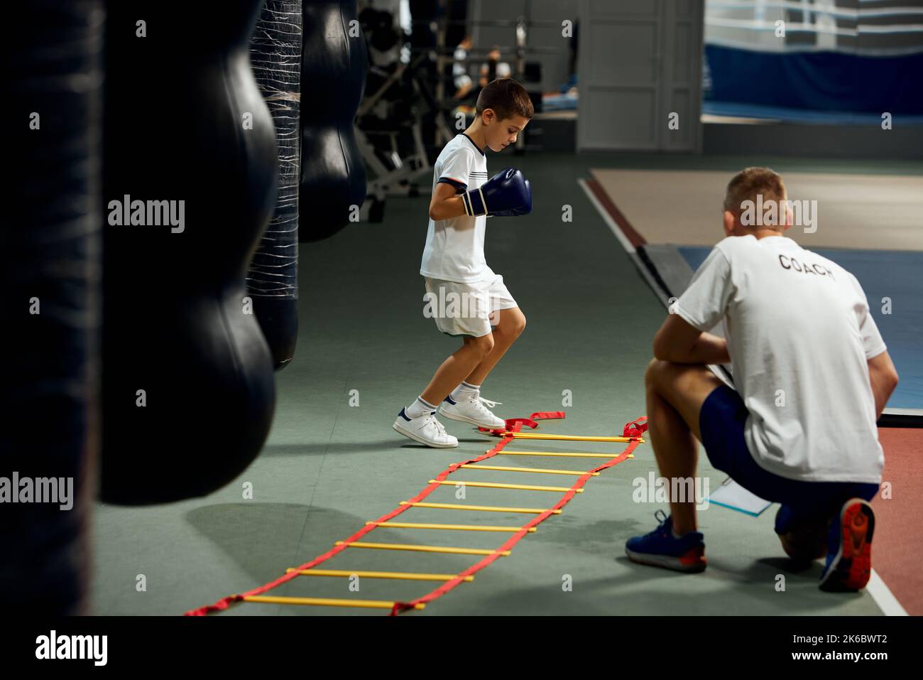 Little boy, beginner boxer workout with personal coach at sports gym ...