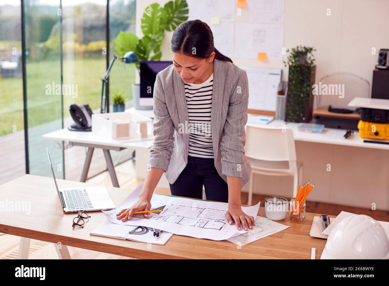 Female Architect Standing Working In Office Studying Plans For New ...