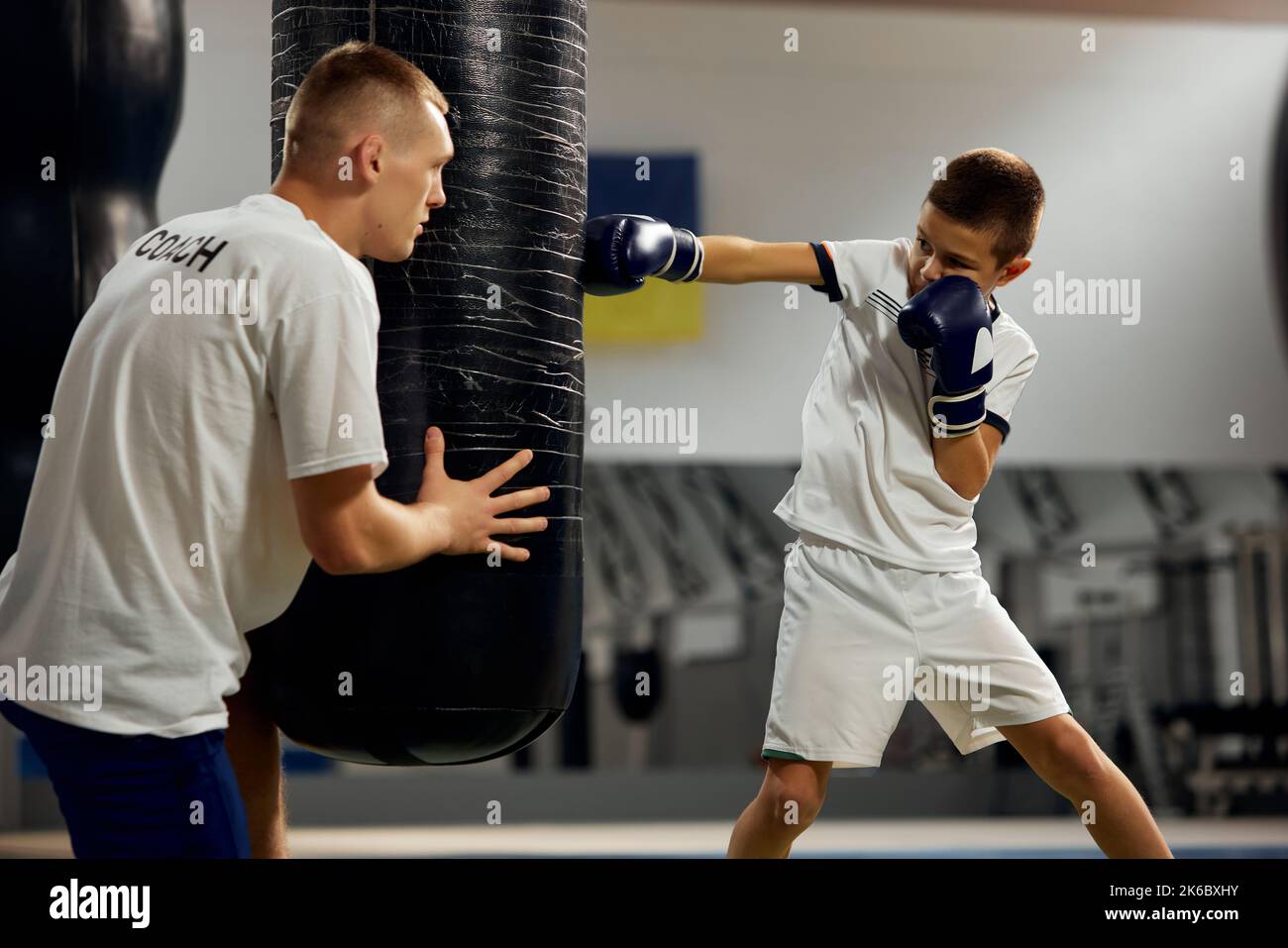 School age boy, beginner boxer practicing punches with personal coach ...