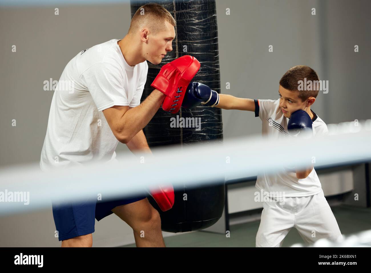 Junior athlete, male boxer training with personal coach at sports gym ...