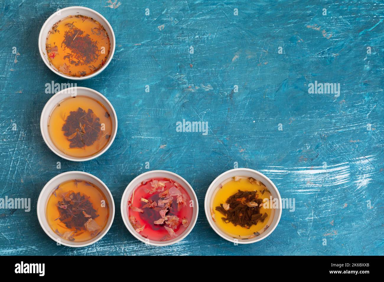 Tea concept. Different kinds of dry tea in ceramic bowls and cups of ...