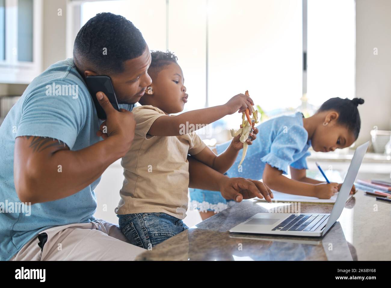 Its a busy day at home. a young father working while looking after hi ...