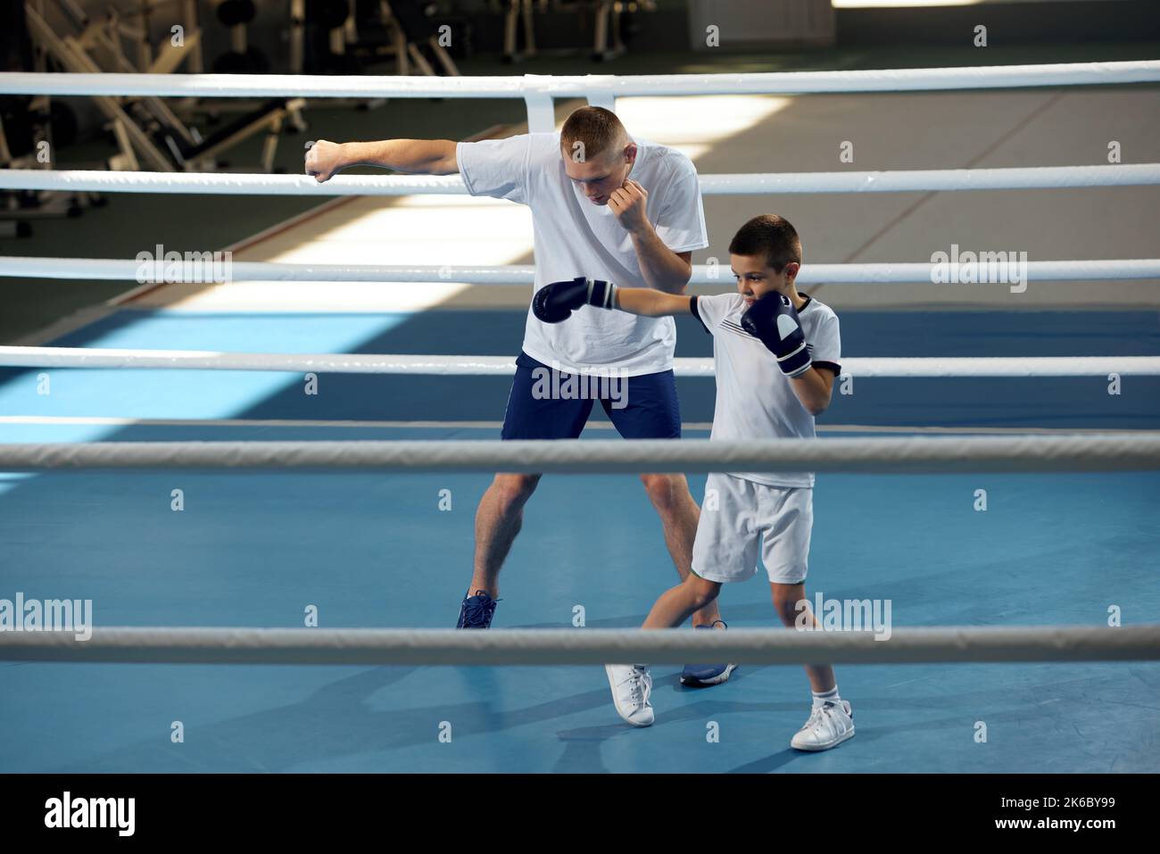 Training in boxing techniques. Junior male boxer practicing with ...