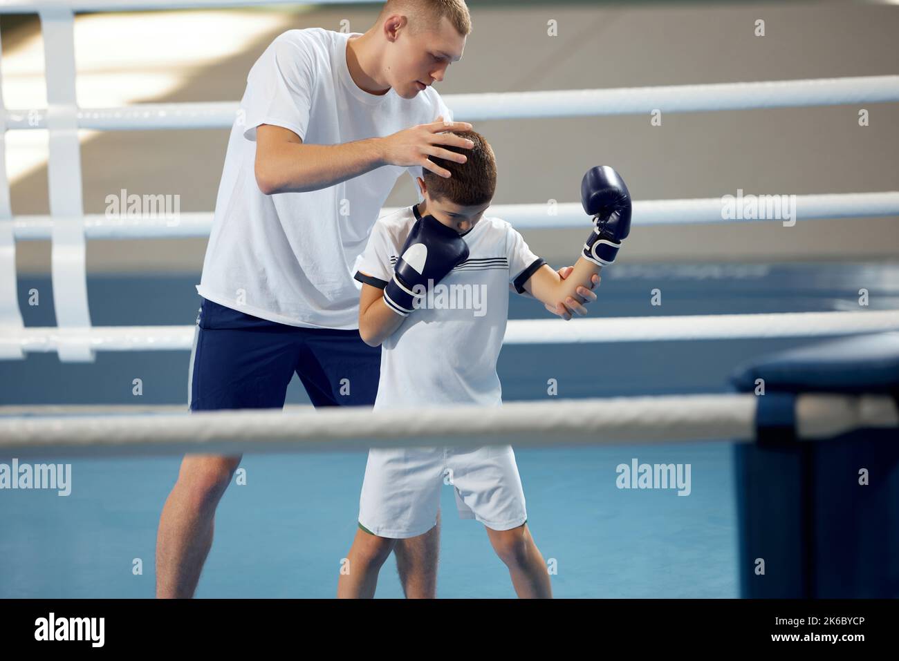 School age boy, beginner boxer practicing punches with personal coach ...