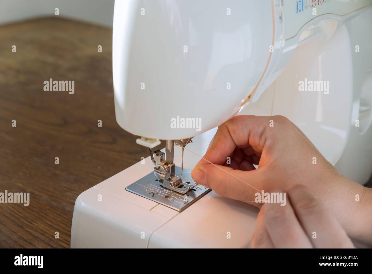 Hand of seamstress pulling thread into needle hole sewing machine Stock ...